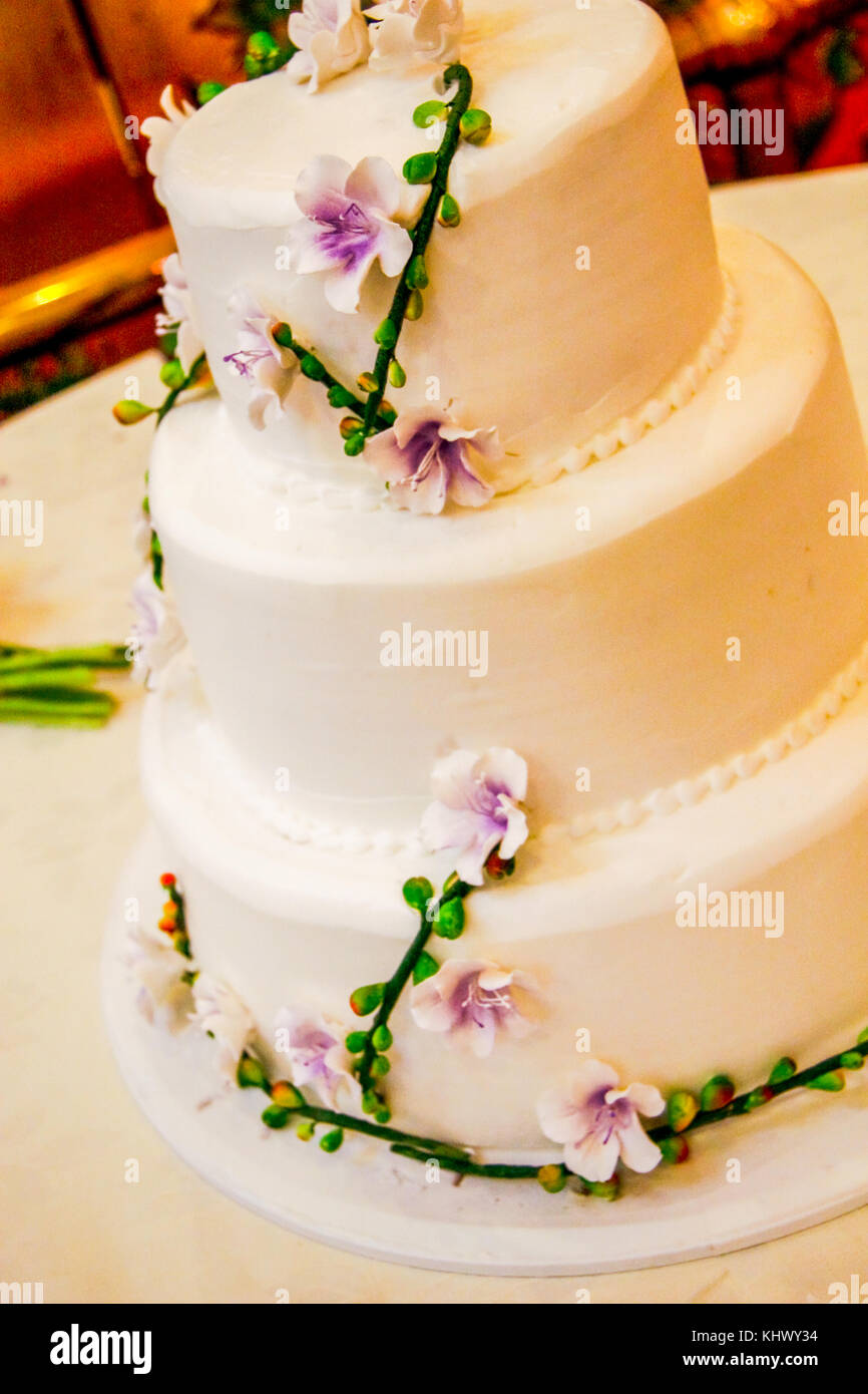 A three layered wedding cake with fresh flowers wrapped around it Stock ...