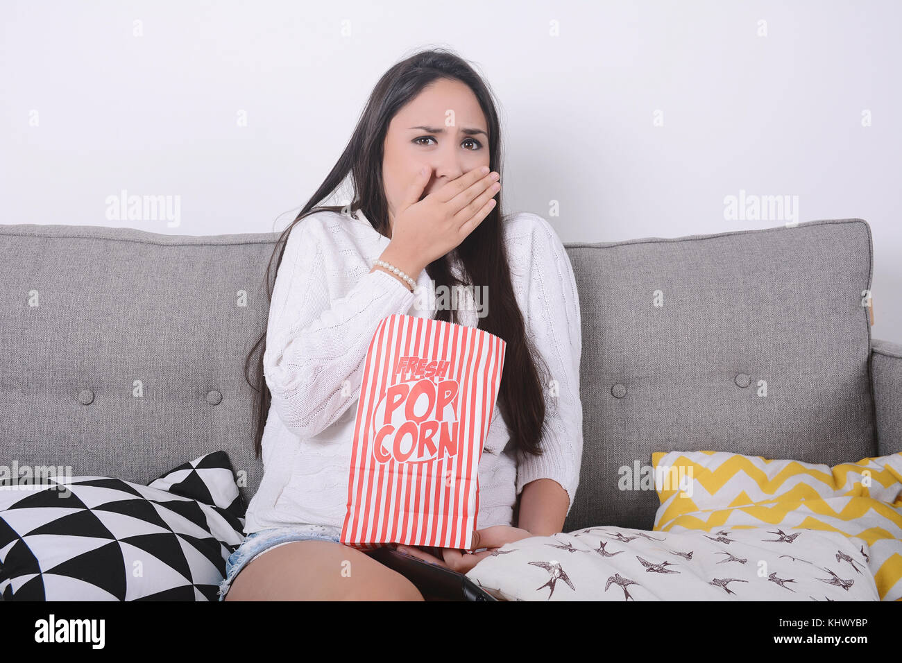 Young woman eating popcorn and watching movies relaxed on couch ...