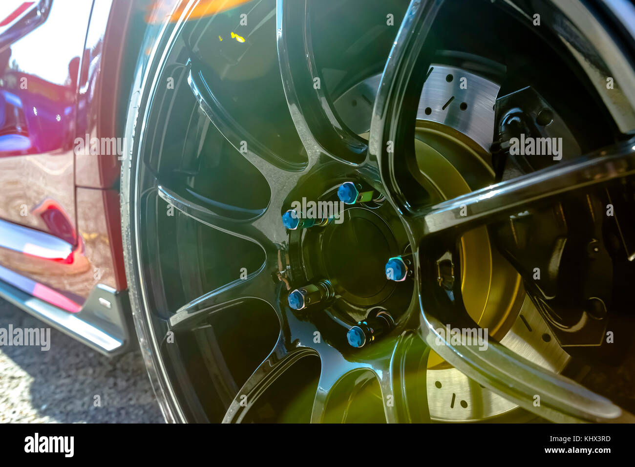 Black rims with blue bolt caps and red car door plus lens flare ...