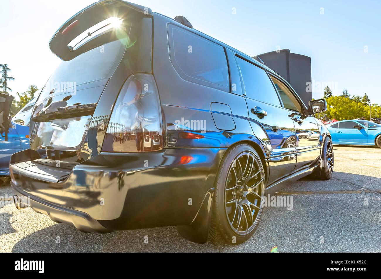 Lens flare with the sun peeking out the spoiler of a black car with the ...
