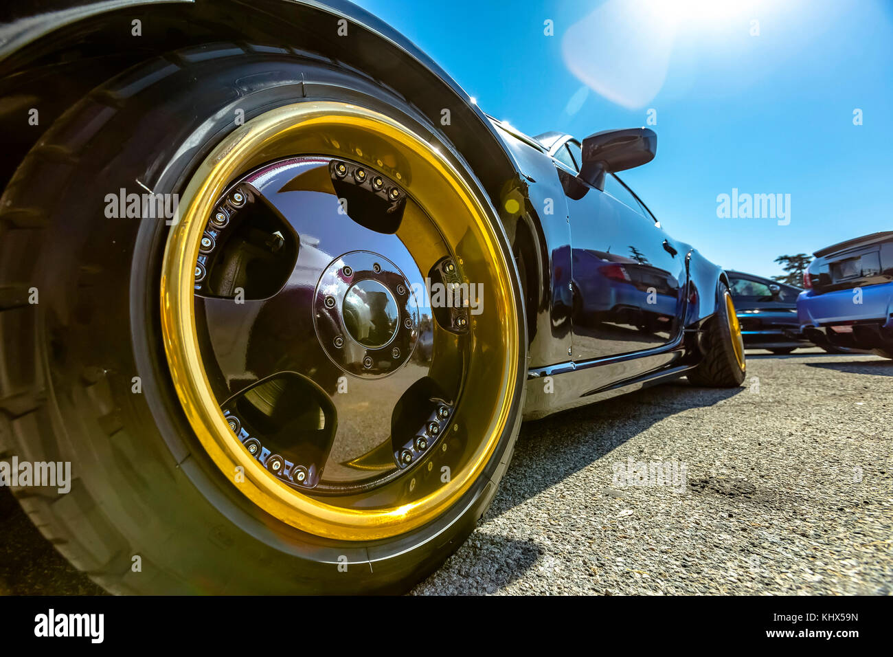 Perspective view of a black car with large golden rims in the front ...