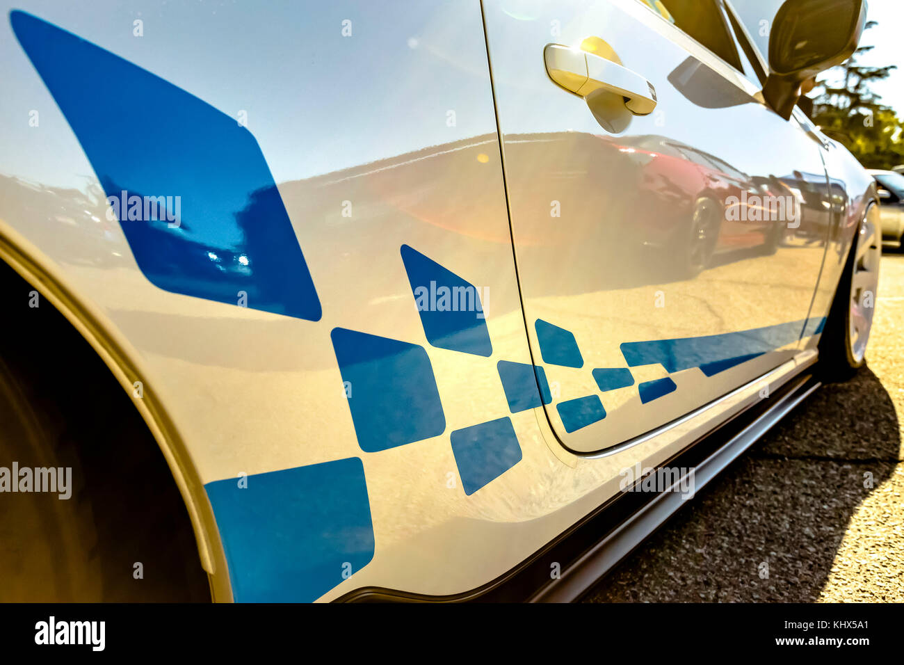 Racing decals on white car with golden reflection on the car handle ...