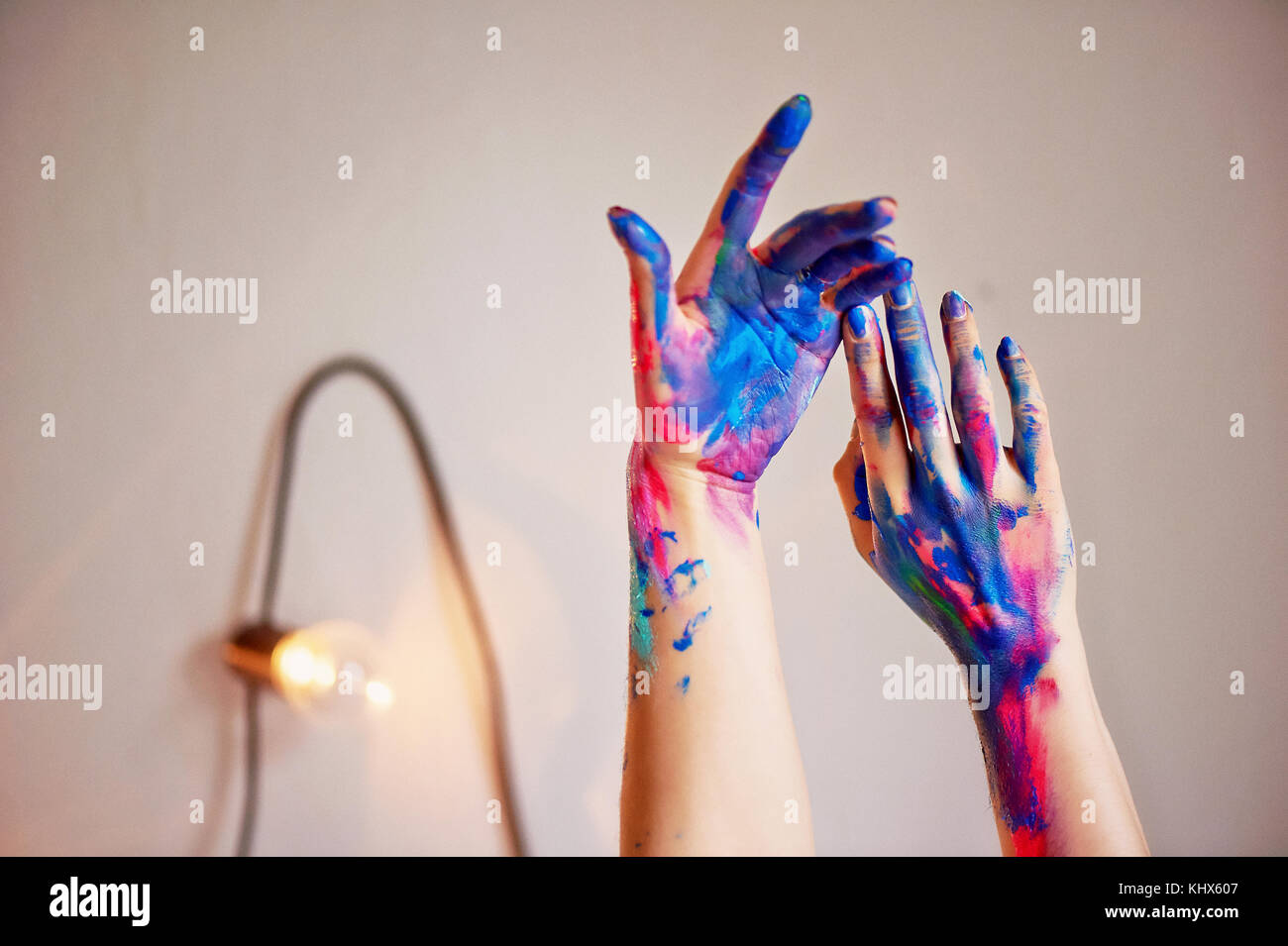 The artist's hand with a thin brush dipped bright fluorescent acrylic ...
