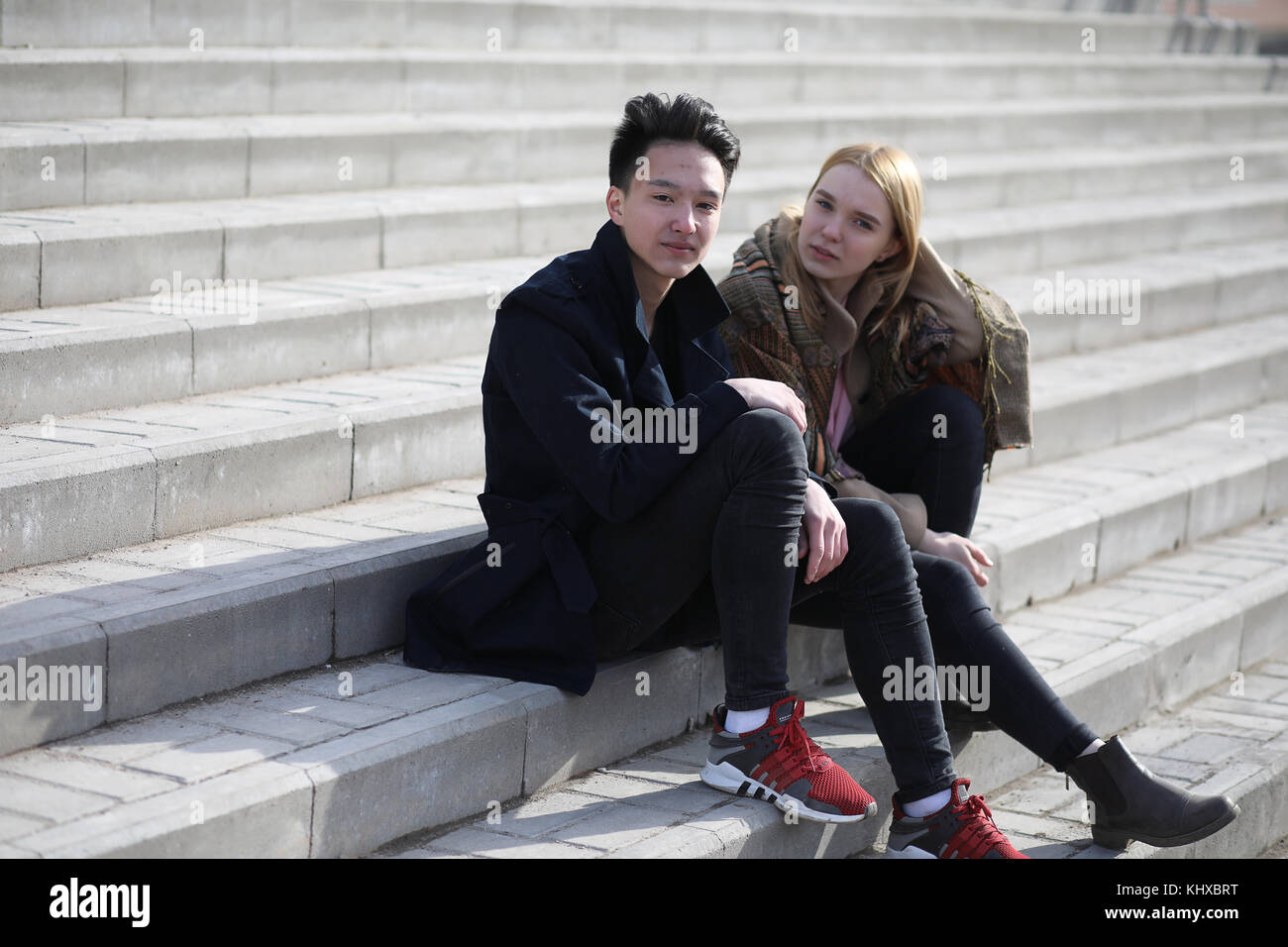 A couple of friends are sitting on the steps Stock Photo - Alamy