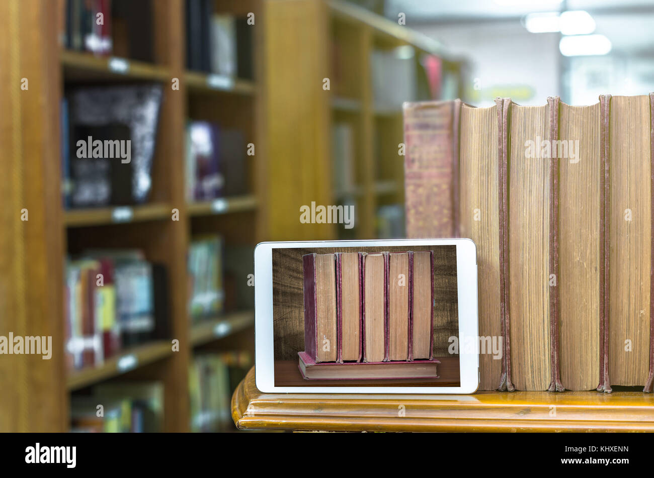 Tablet computer with old books on the wood table in library, Education ...
