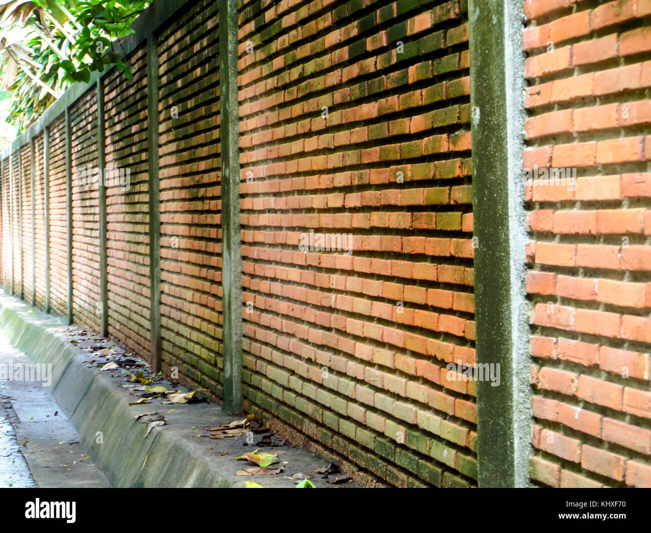ancient brick wall has erosion and damage by wind and water beside way ...