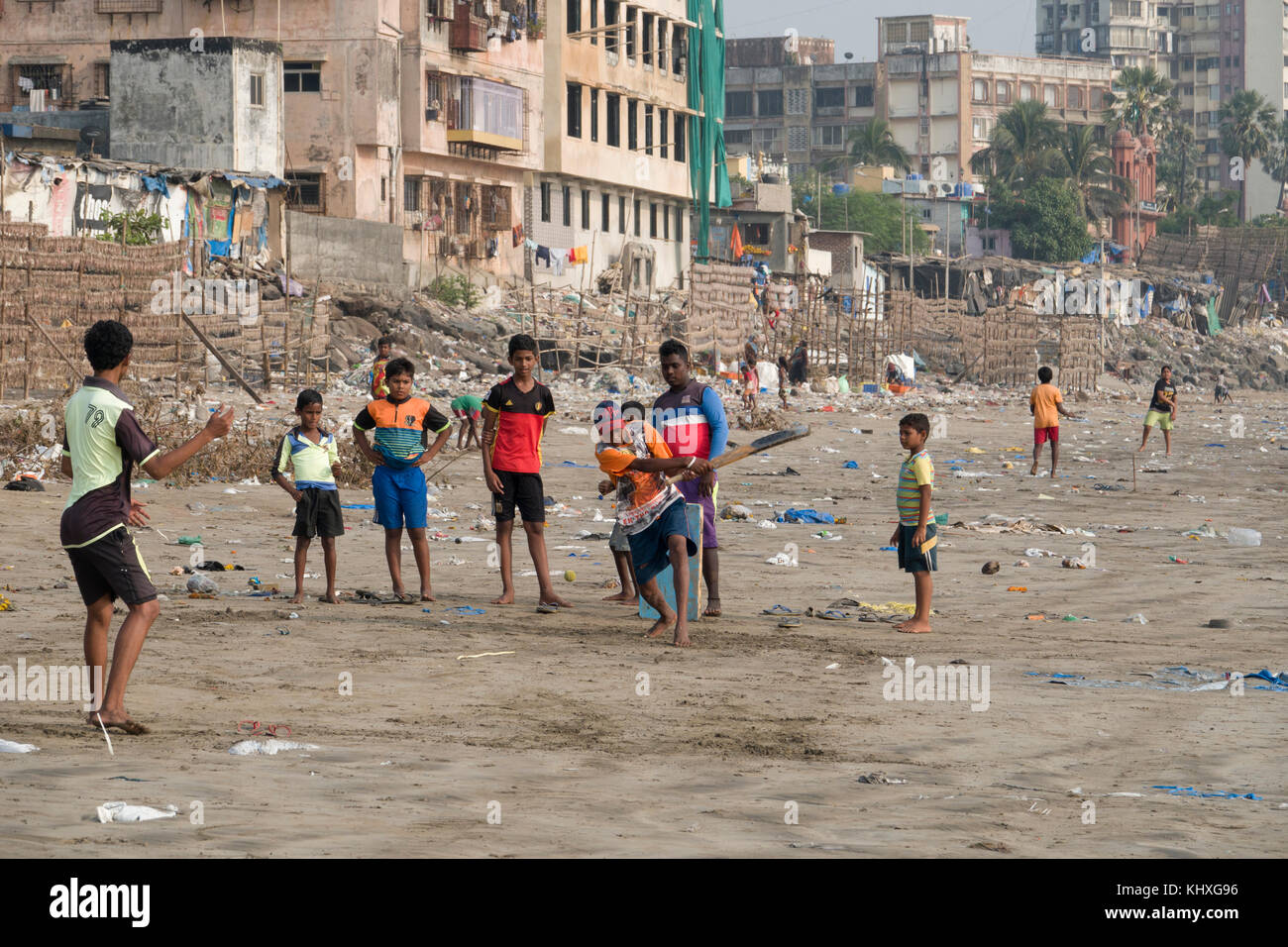 Indian teenage boys playing game of cricket among plastic garbage and ...