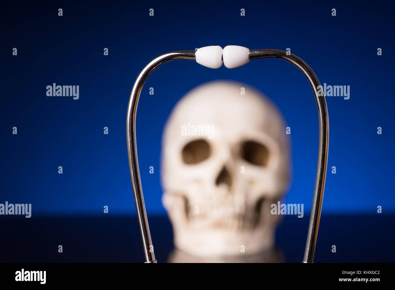 Stethoscope i focus and blurry skull isolated on black blue background ...