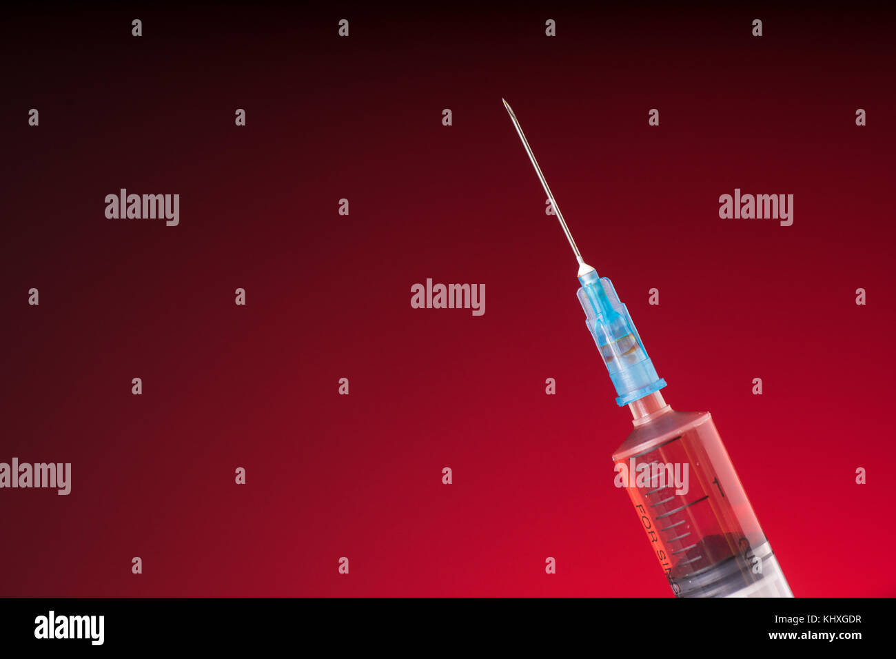 Isolated medical syringe on red, dark background Stock Photo - Alamy