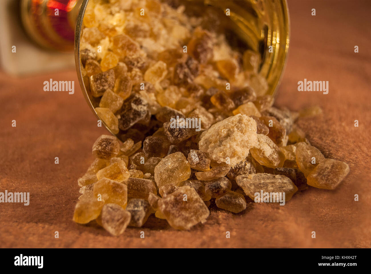 Brown cane sugar is poured out of the gold cup by pieces. The concept ...