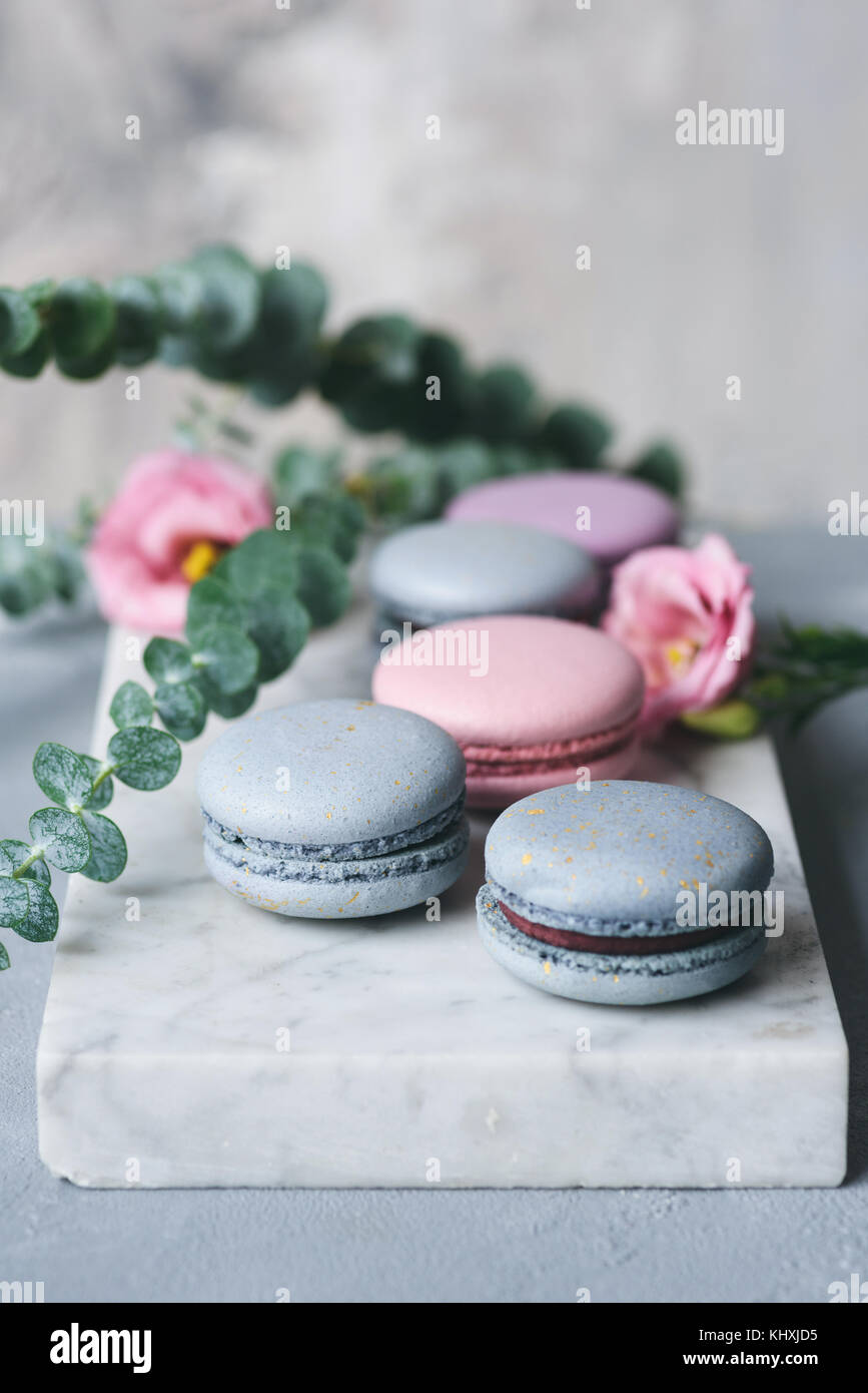 Pastel macarons or macaroon on marble table with pink flowers. French ...