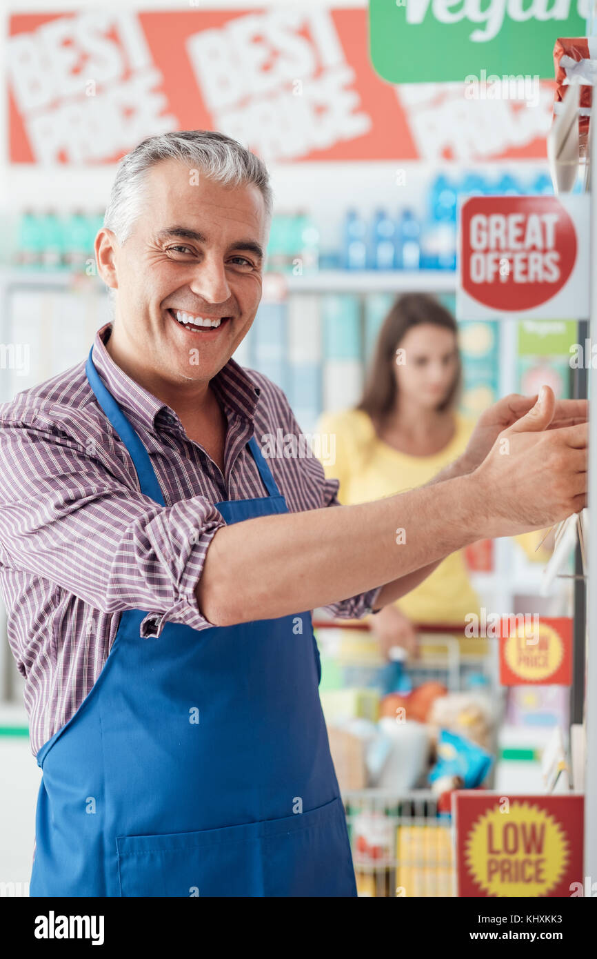 Professional supermarket clerk working in the store aisle, he is ...