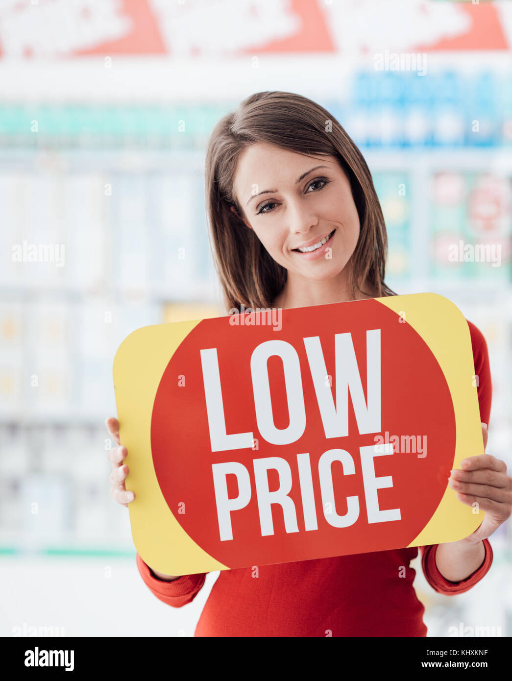 Smiling woman shopping at the supermarket and holding a discount sign ...
