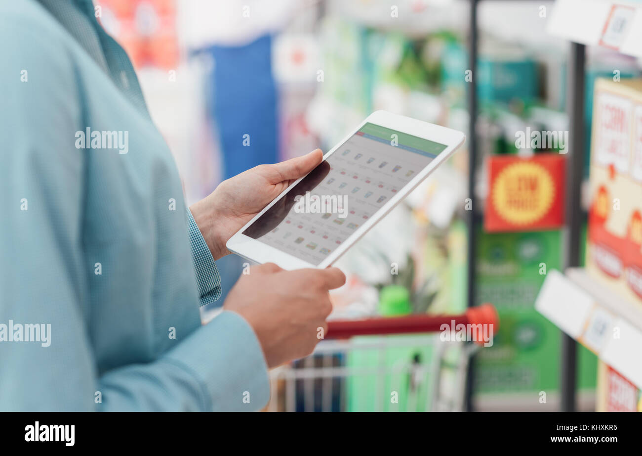 Woman shopping at the supermarket, she is connecting with her digital ...