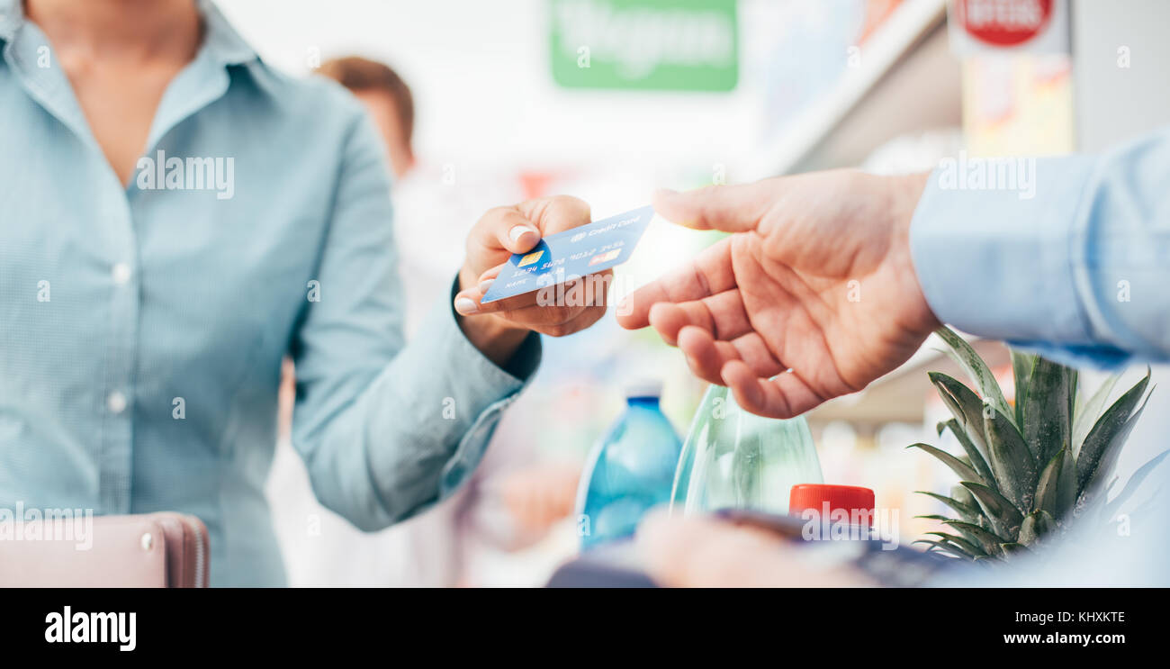 Woman at the supermarket checkout, she is paying using a credit card ...