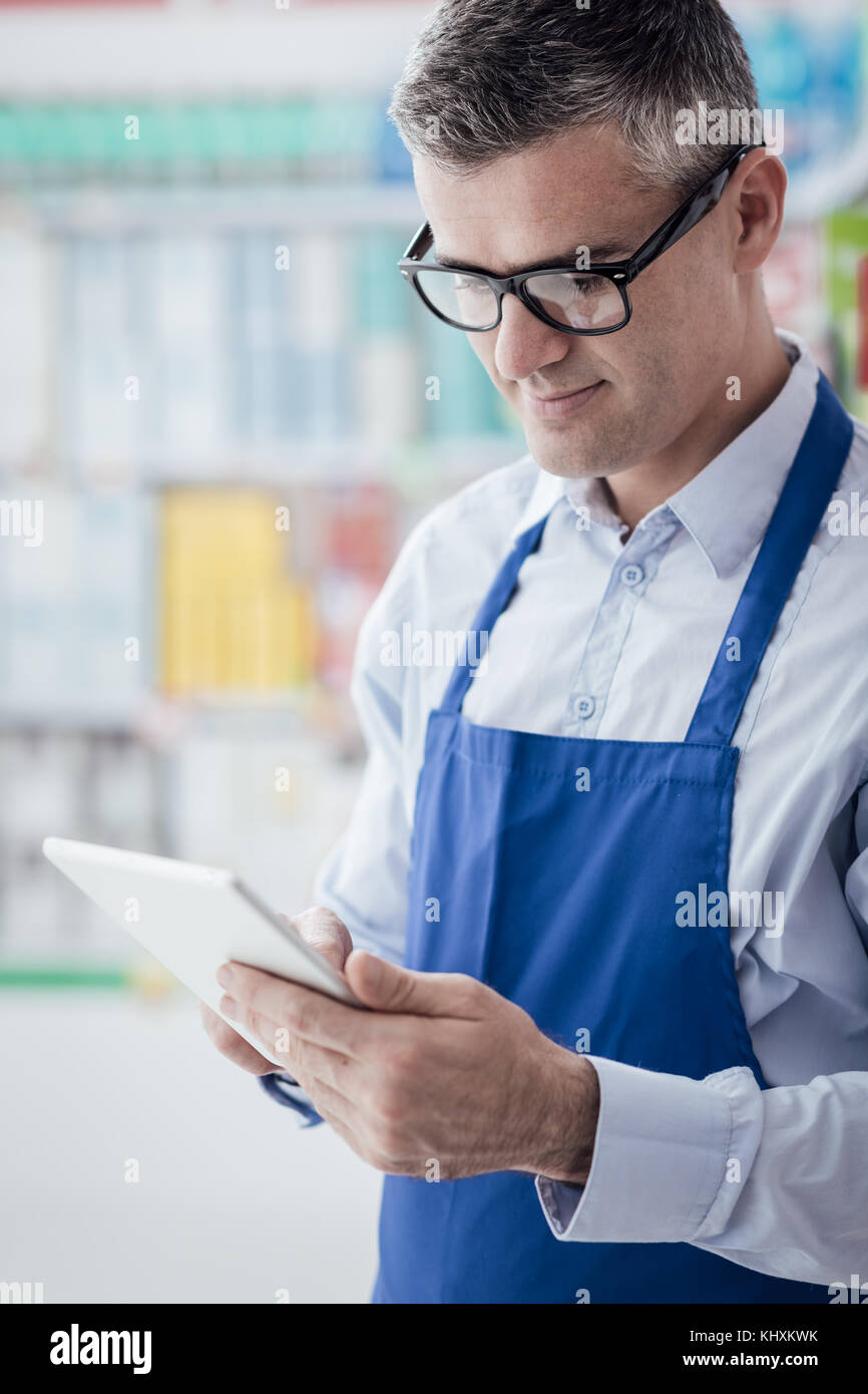 Professional supermarket clerk working with a digital tablet, he is ...