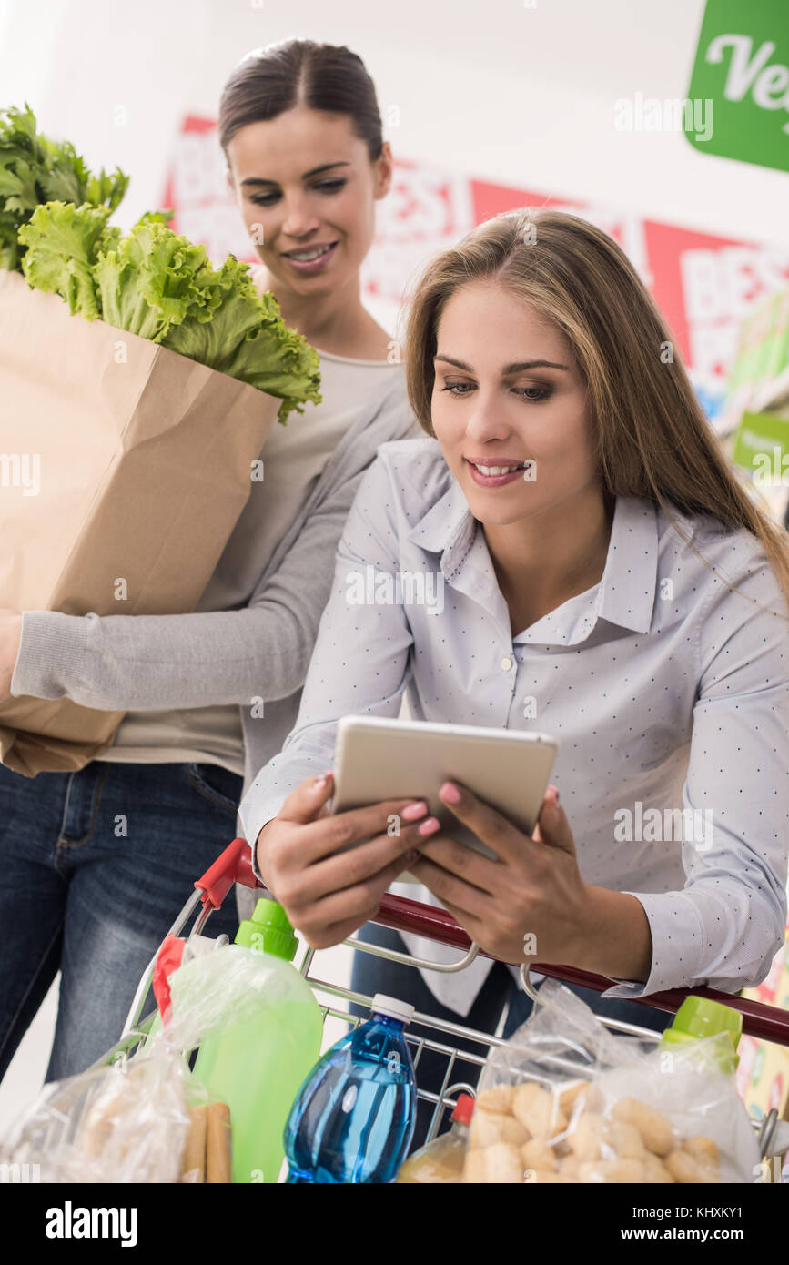 Young women doing grocery shopping together at the supermarket, one is ...