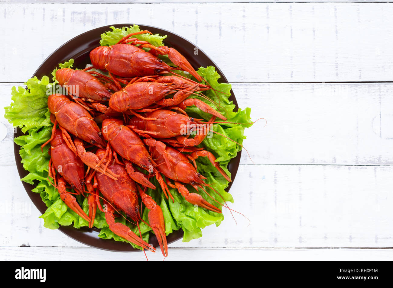 A large pile of boiled crawfish on a ceramic plate on a white wooden ...