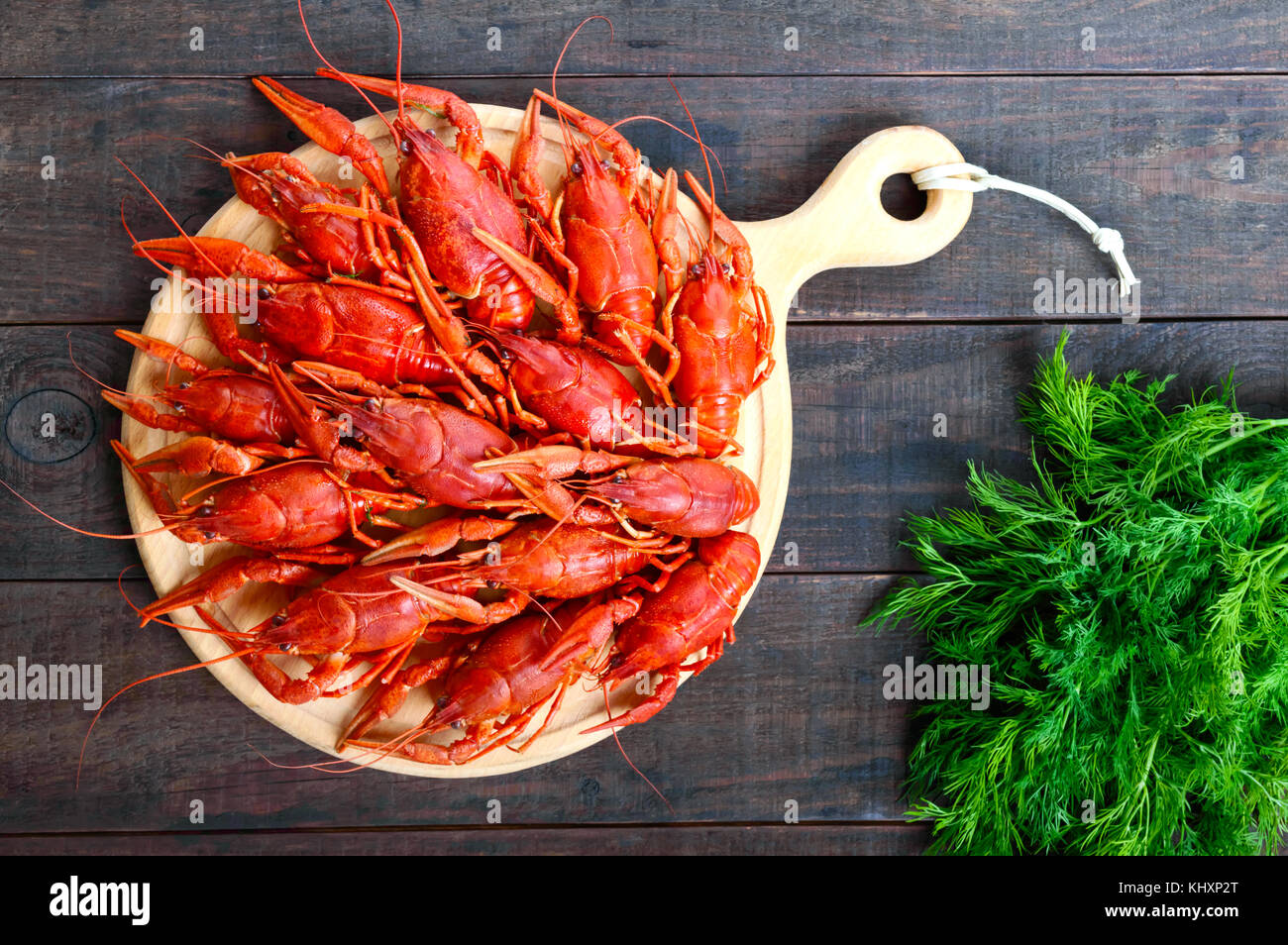 A pile of tasty boiled crawfish on a round wooden tray on a dark table ...