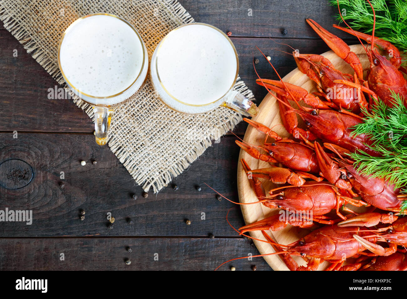 A pile of tasty boiled crawfish on a round wooden tray and two mugs of ...