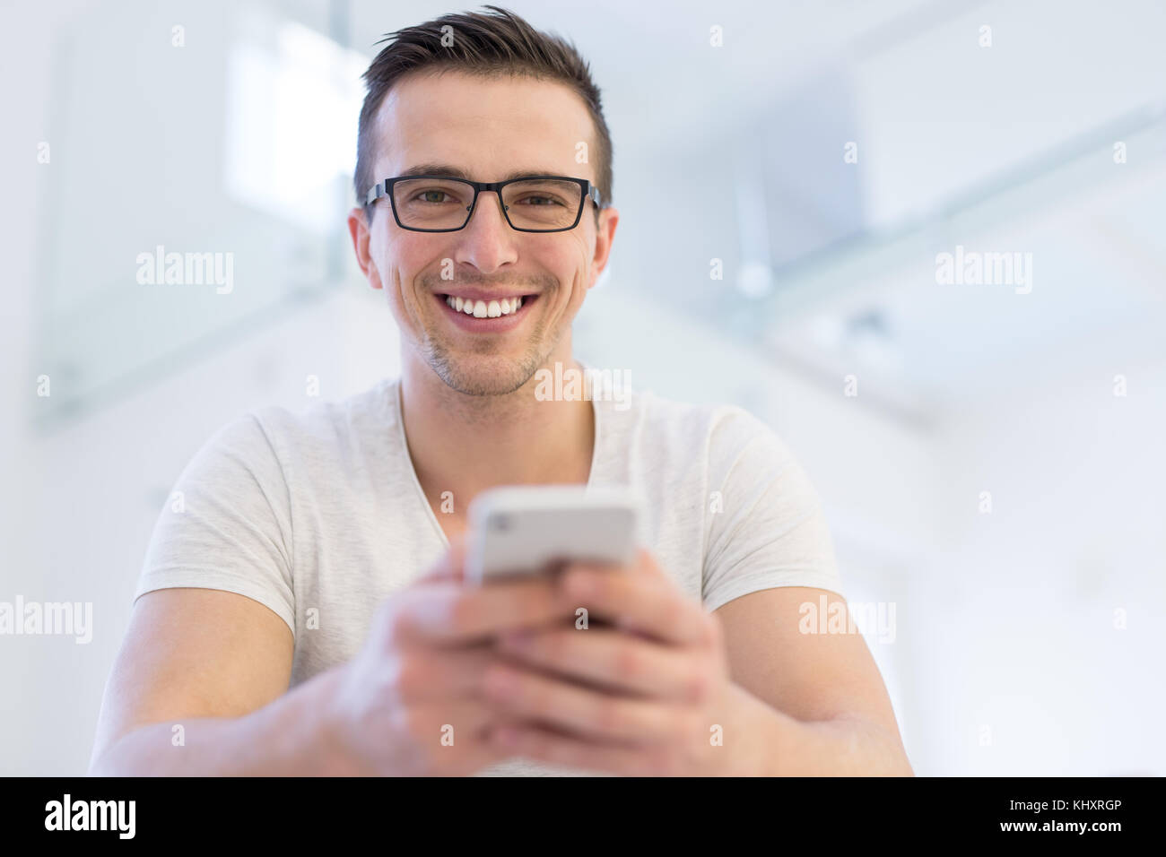 Handsome casual young man using a mobile phone at home Stock Photo - Alamy