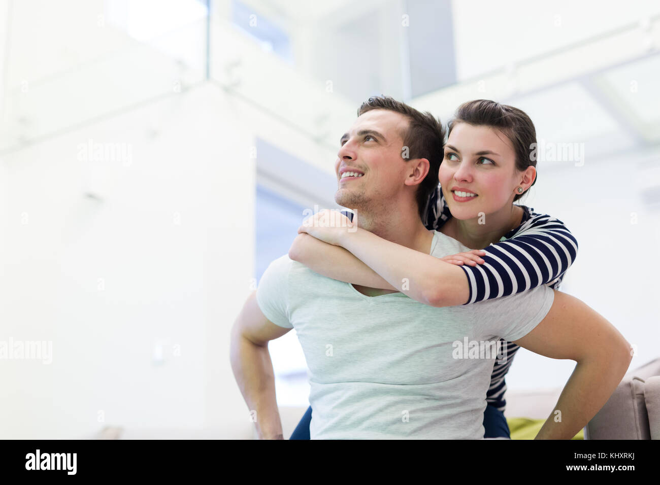 happy young man piggybacking his girlfriend at home Stock Photo - Alamy