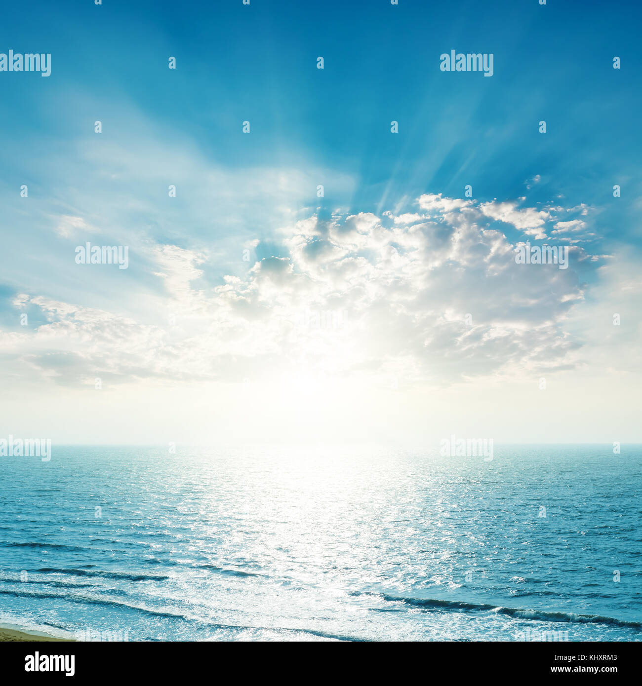 bright sunset in blue sky with clouds over sea Stock Photo - Alamy