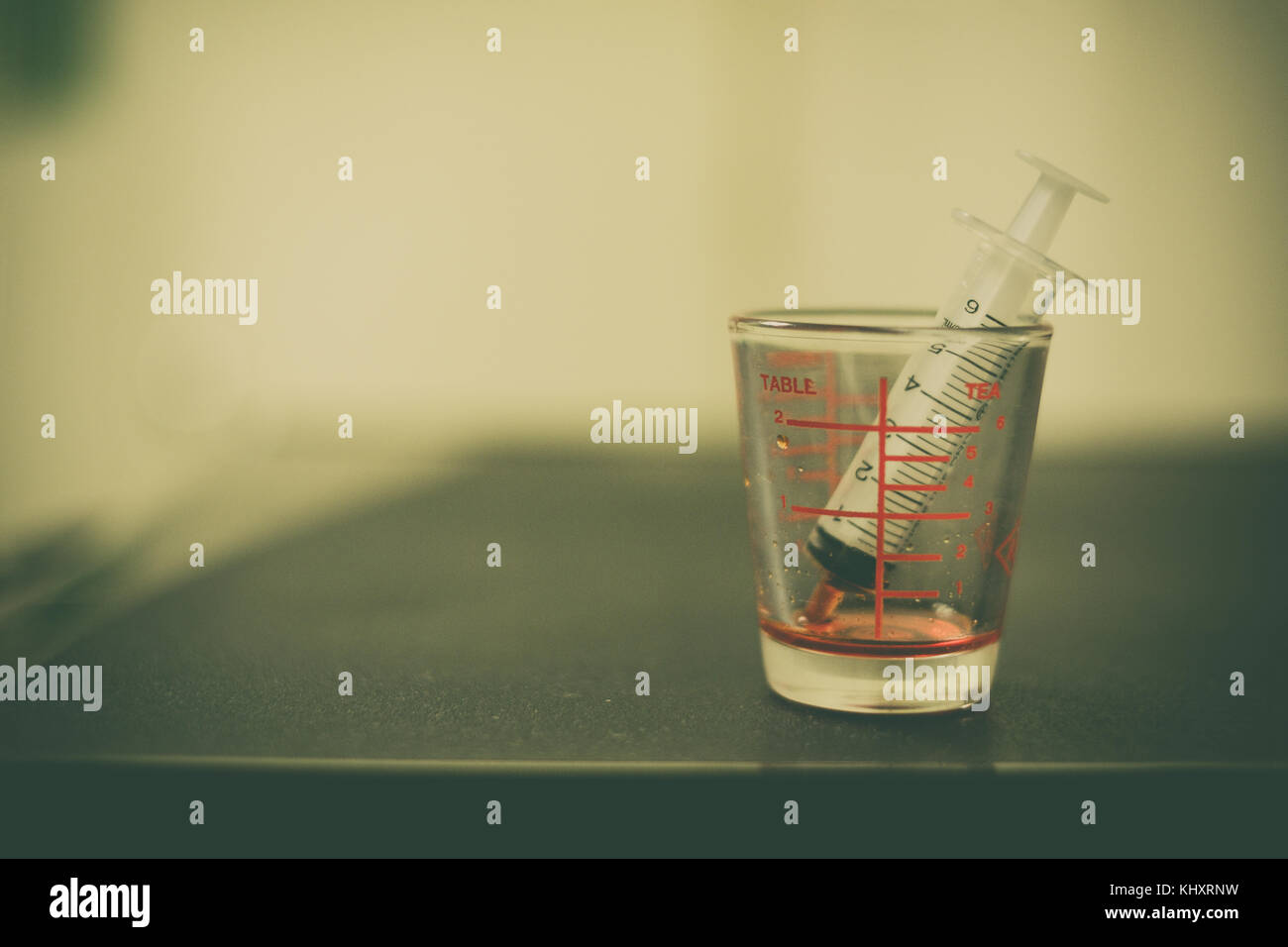 syringe with medicine syrup in a Pharmaceutical glass measuring cup for ...