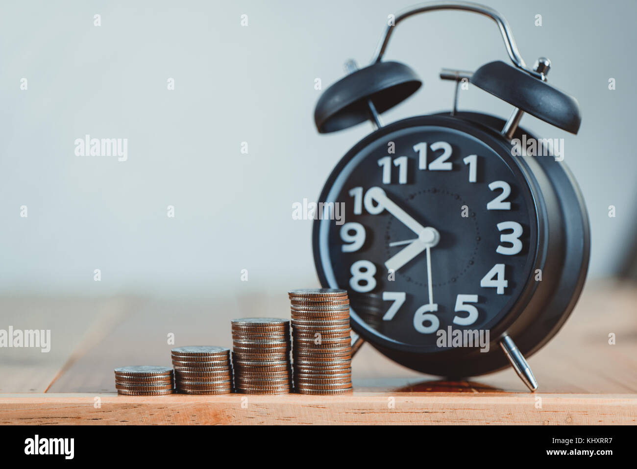 Alarm clock and step of coins stacks on working table, time for savings ...