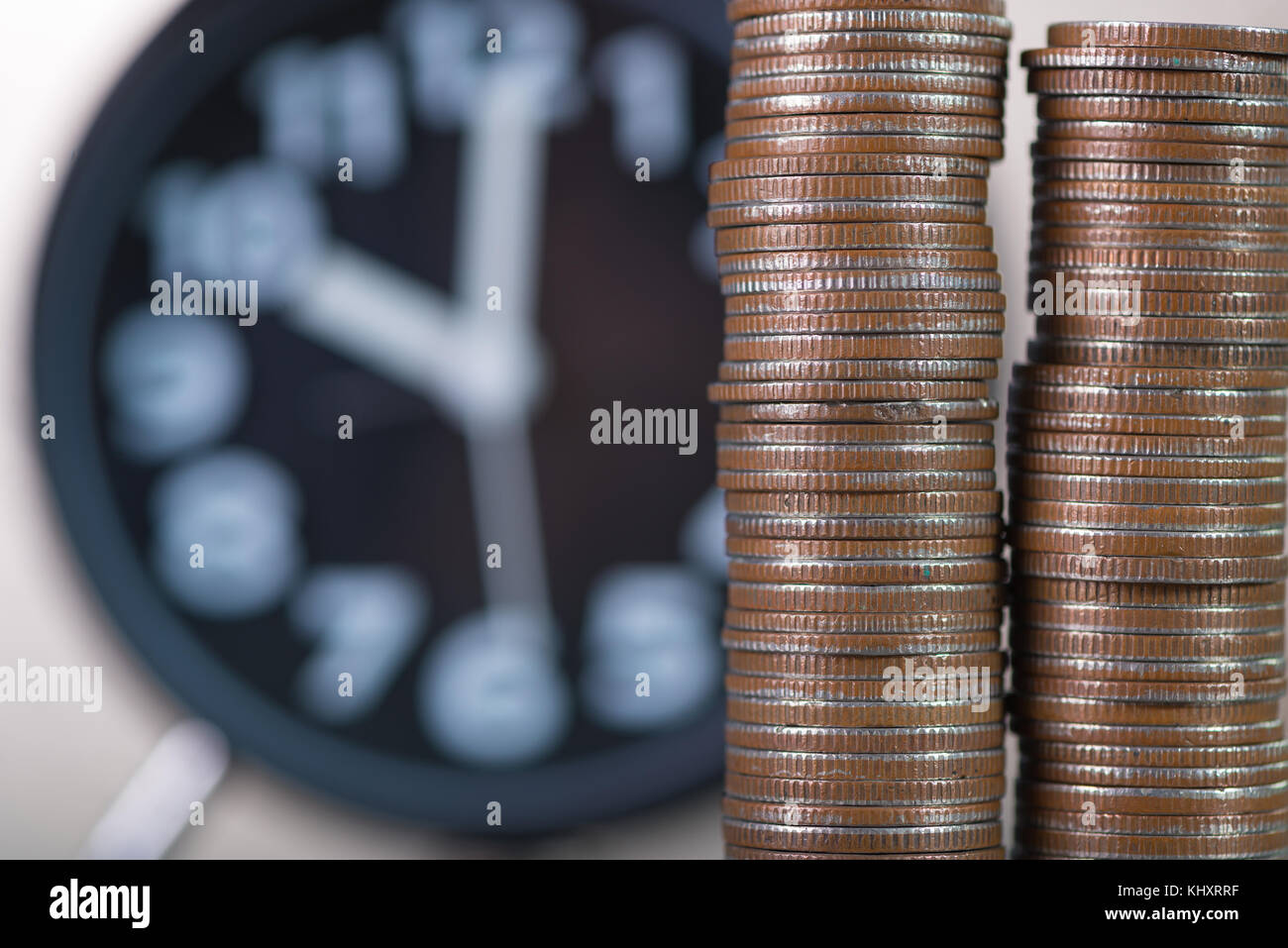 Alarm clock and piles of coin on working table, time for savings money ...