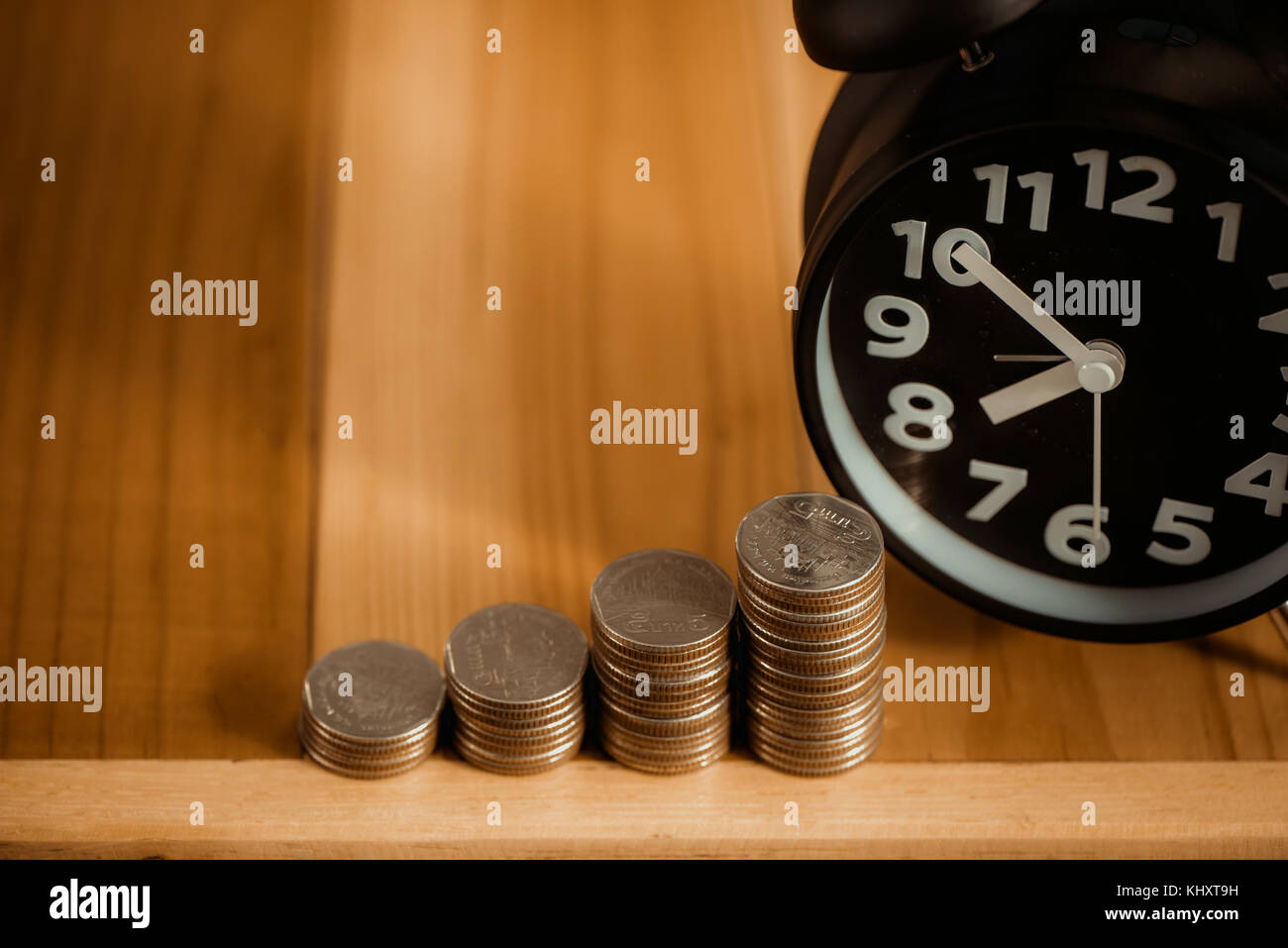 Alarm clock and step of coins stacks on working table, time for savings ...