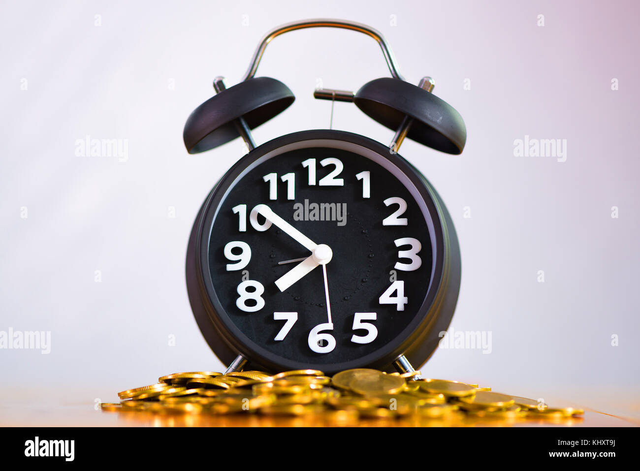 Alarm clock and piles of coin on working table, time for savings money ...