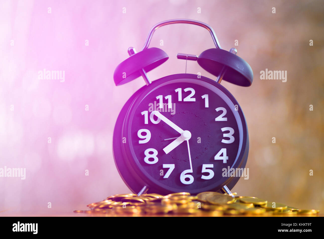 Alarm clock and piles of coin on working table, time for savings money ...