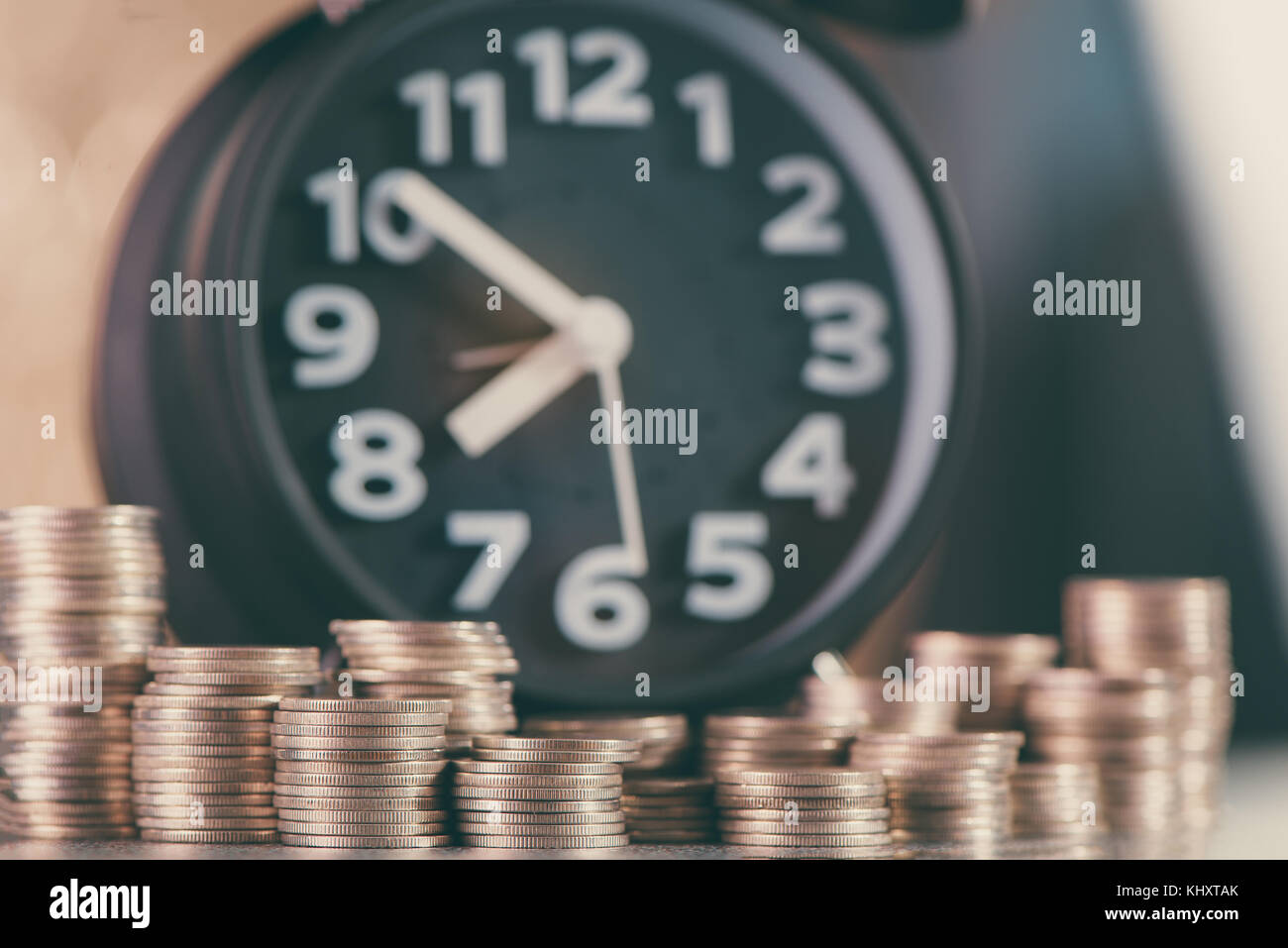 Alarm clock and step of coins stacks on working table, time for savings ...