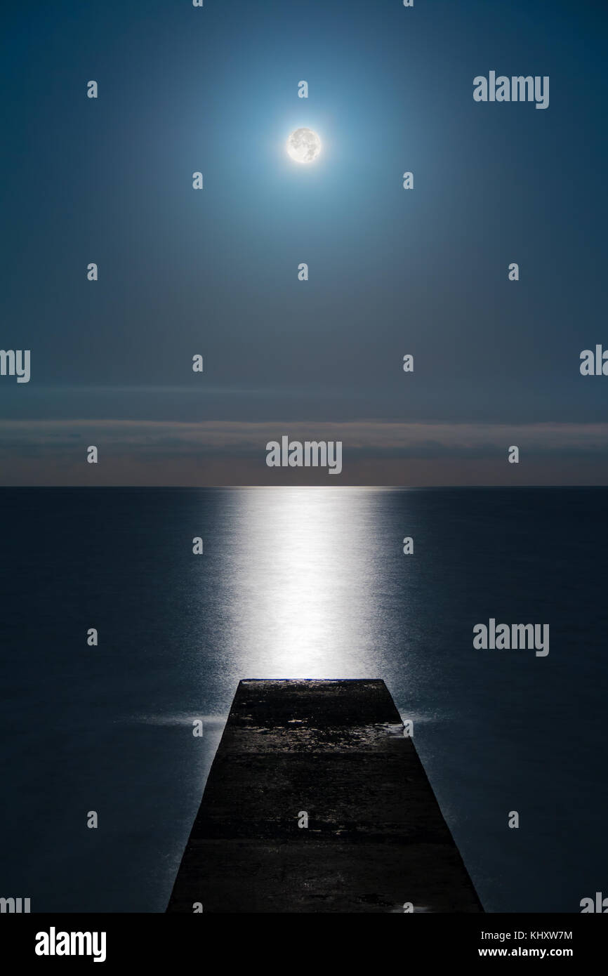 Seascape with the full moon over the sea and the mole in line with the ...