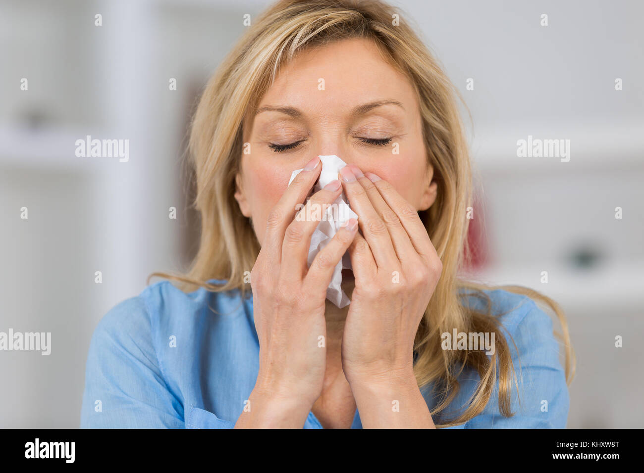 woman with cold blowing her nose Stock Photo - Alamy