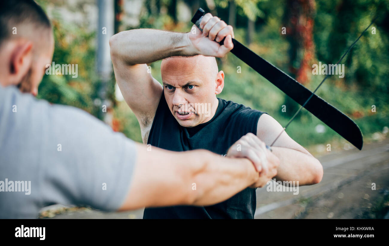 Martial arts instructor demonstrates machete fighting concept. Long ...