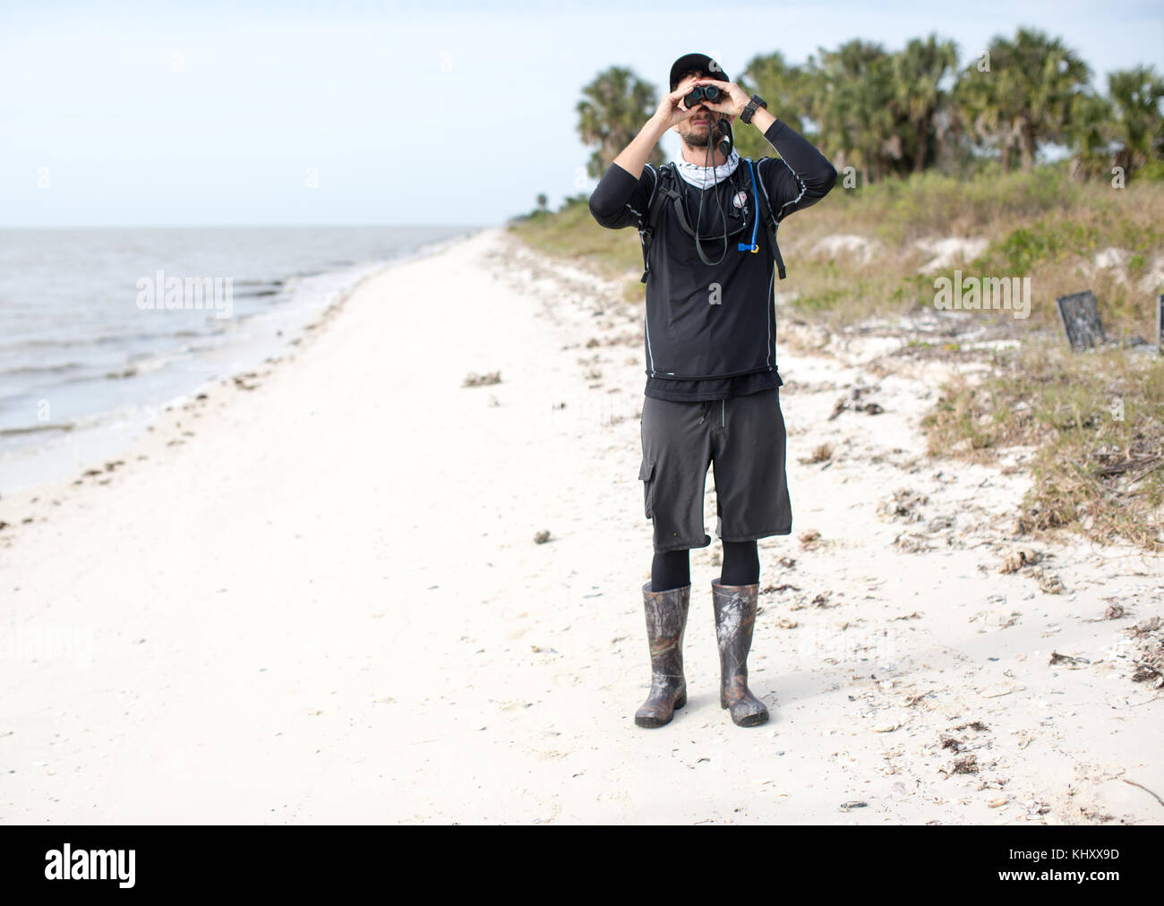 Man standing on beach, looking through binoculars, front view Stock ...