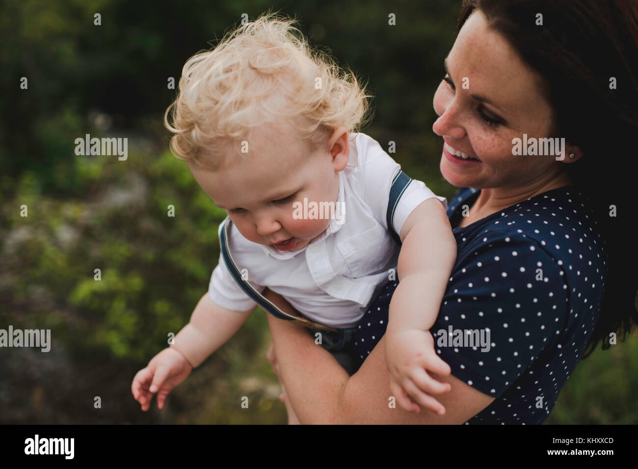Mid adult woman carrying toddler son in arms Stock Photo - Alamy