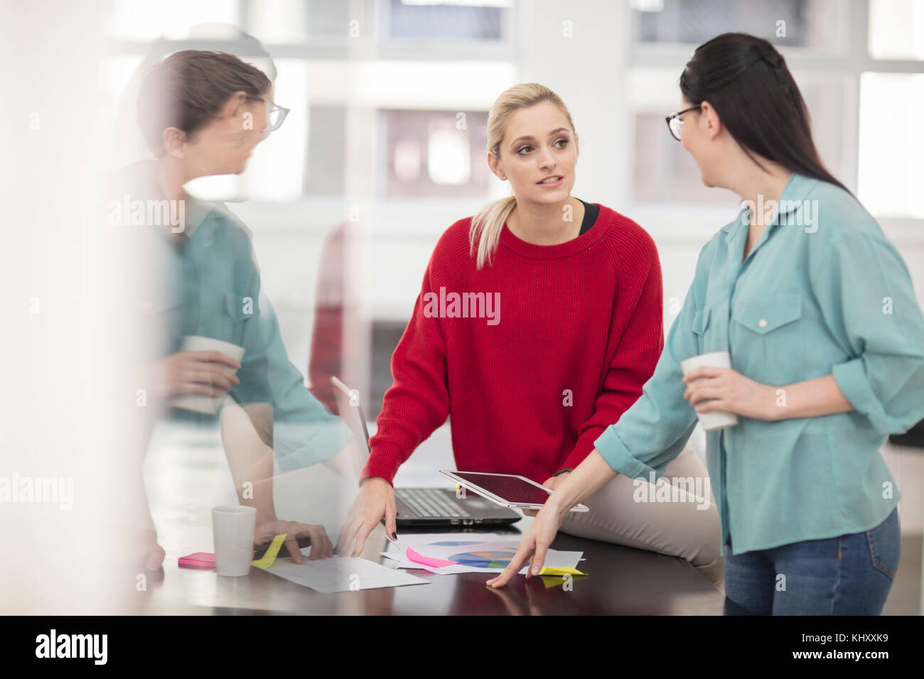 Two young female office workers meeting at office desk Stock Photo - Alamy