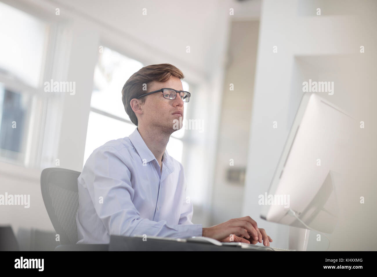 Young male office worker typing at desktop computer Stock Photo - Alamy
