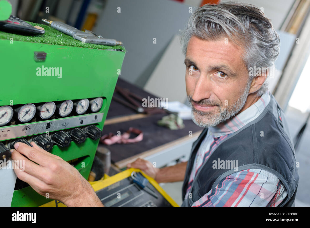 Portrait of man adjusting industrial machine Stock Photo - Alamy