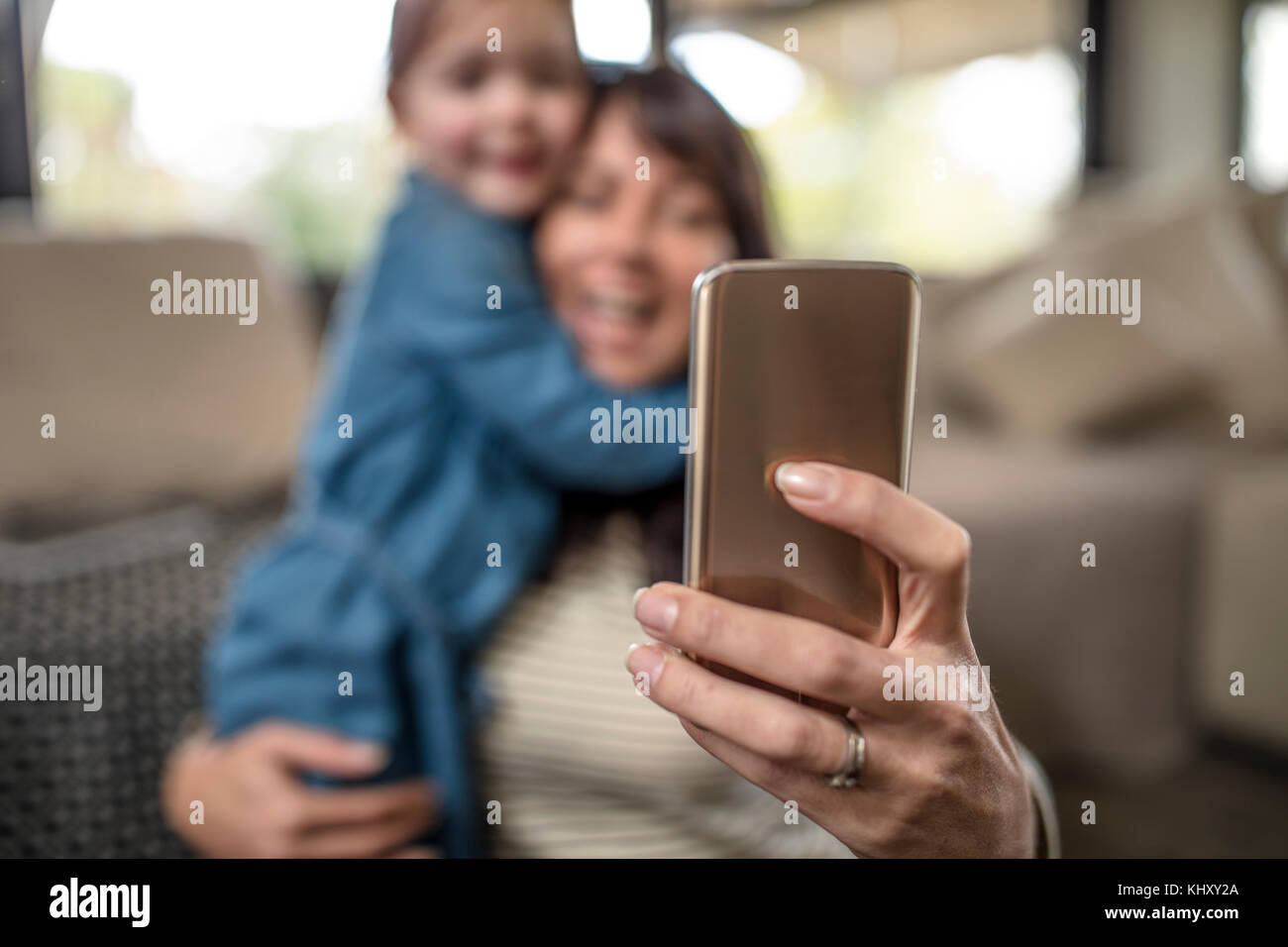 Shallow focus of mature woman taking smartphone selfie with daughter in ...