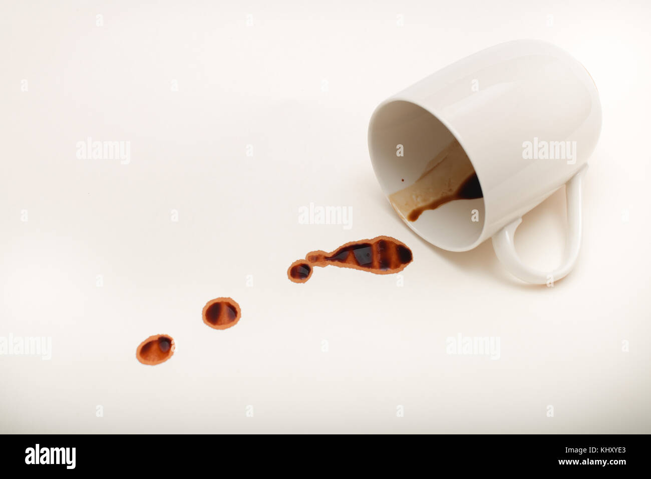 Close up view of empty coffee mug with wet coffee drops on white paper ...