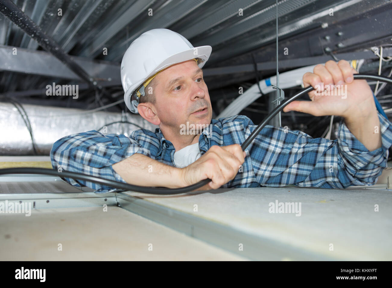 Electrician bending cable in roof space Stock Photo - Alamy