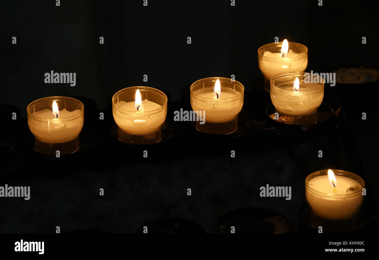 White translucent candles burning in dark church, close up, high angle ...