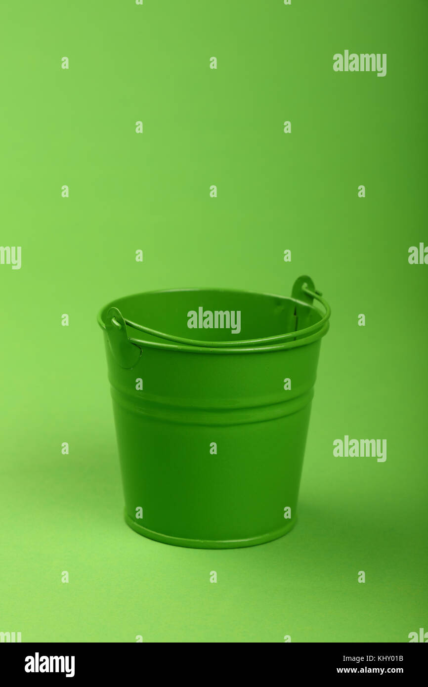 One small green painted metal empty toy bucket over green paper ...