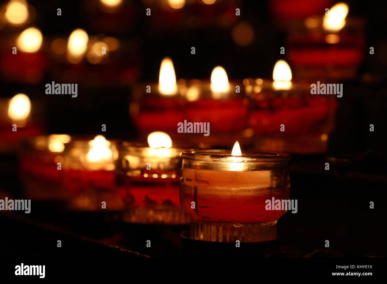 Red glass translucent candles burning in dark church, close up, low ...
