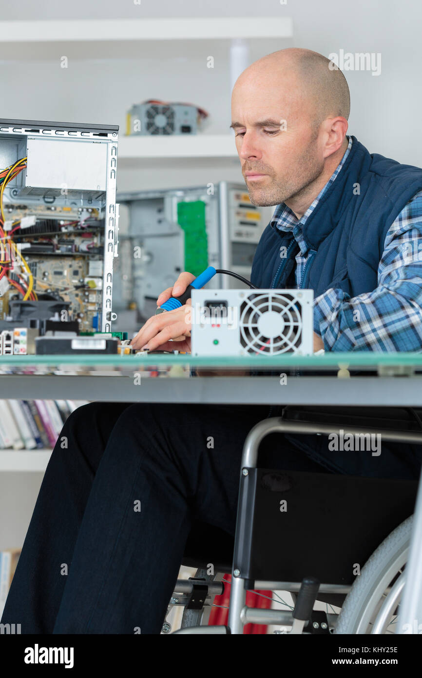 man in wheelchair fixing computer Stock Photo - Alamy