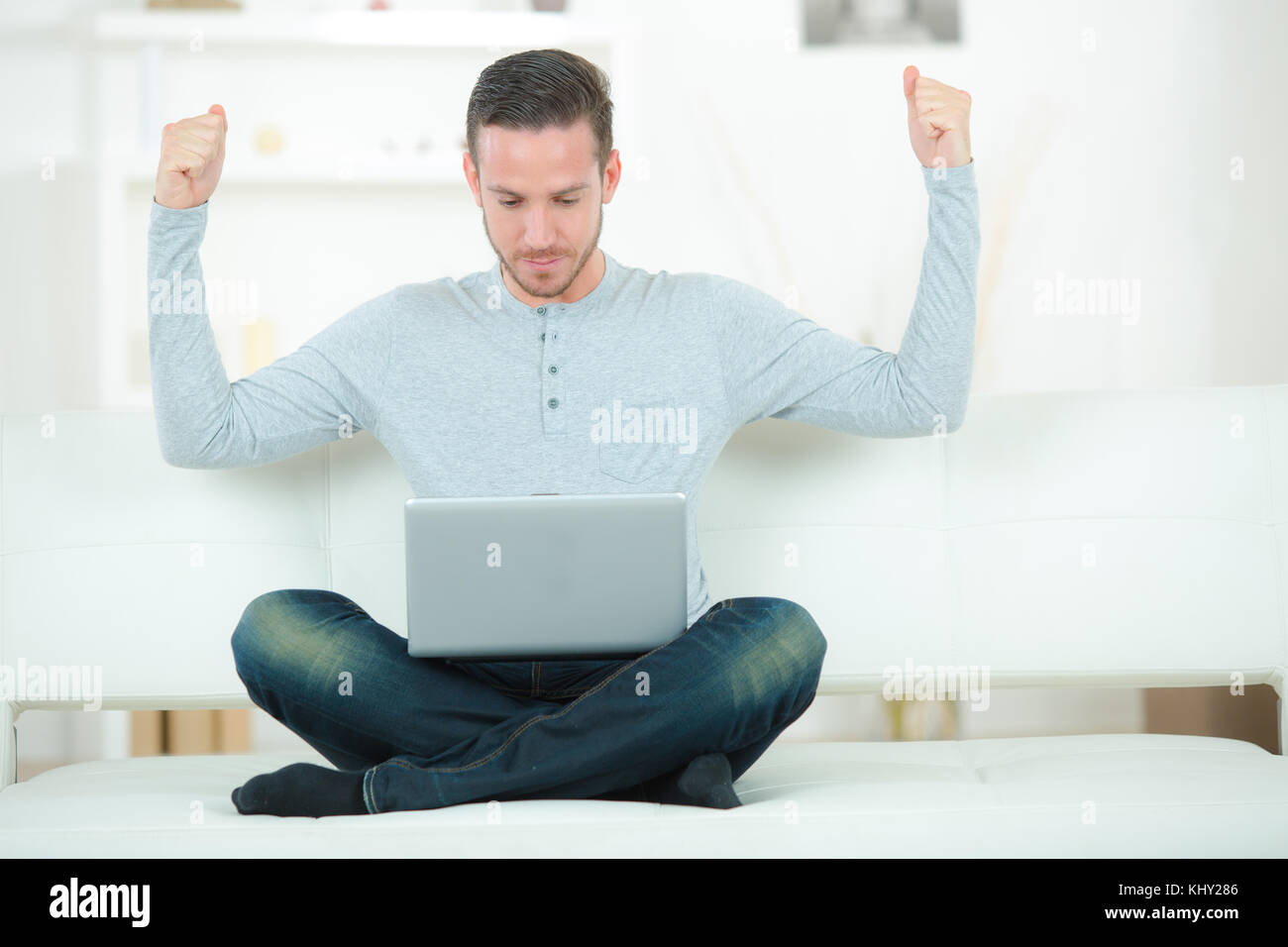 young man with arms raised with computer laptop celebrating success ...